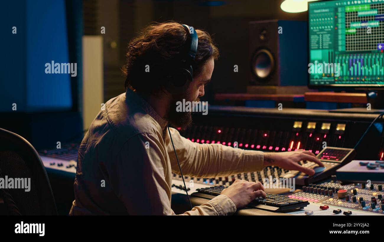 Audio expert operating motorized faders and mixing console in control ...