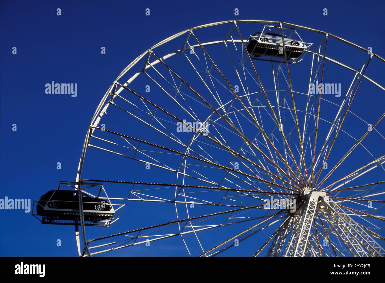 Display of vehicles on a ferris wheel on a blue sky background in ...