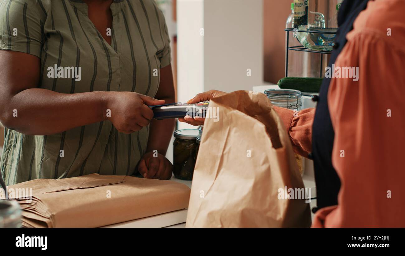 Woman client paying for bio organic groceries at counter, using card ...