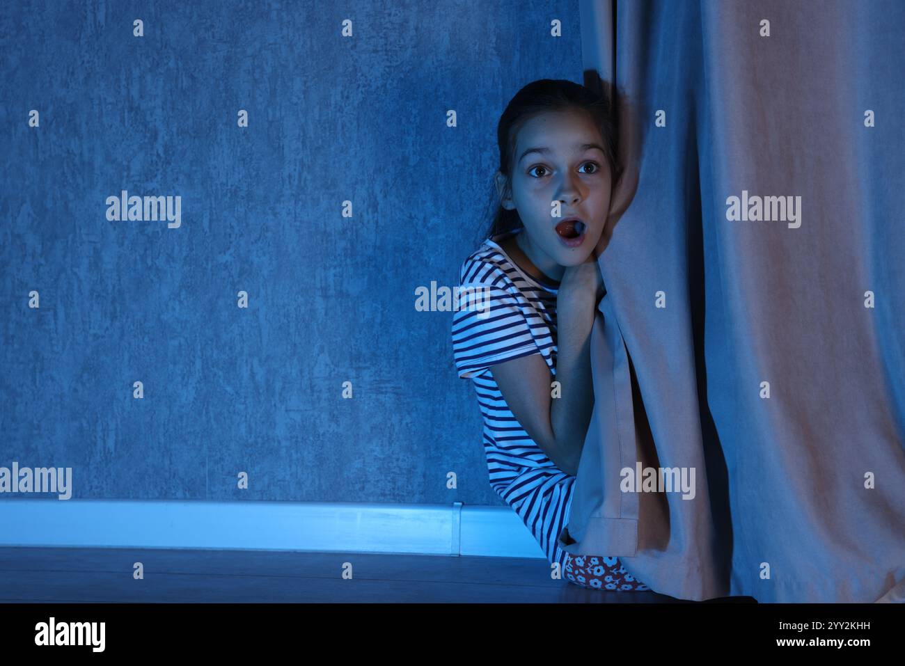 Scared girl hiding behind curtain at night. Space for text Stock Photo ...