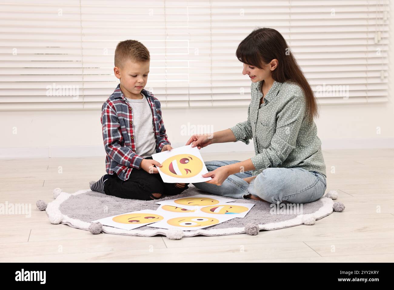 Autism therapy. Little boy choosing emoticon with smiling psychologist ...