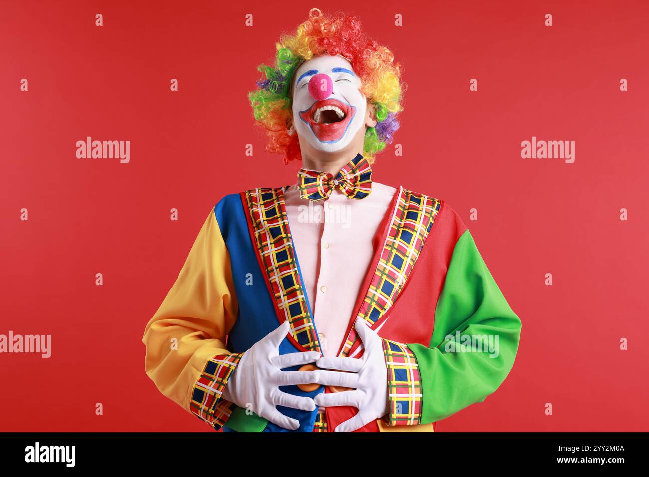 Portrait of clown laughing on red background Stock Photo - Alamy