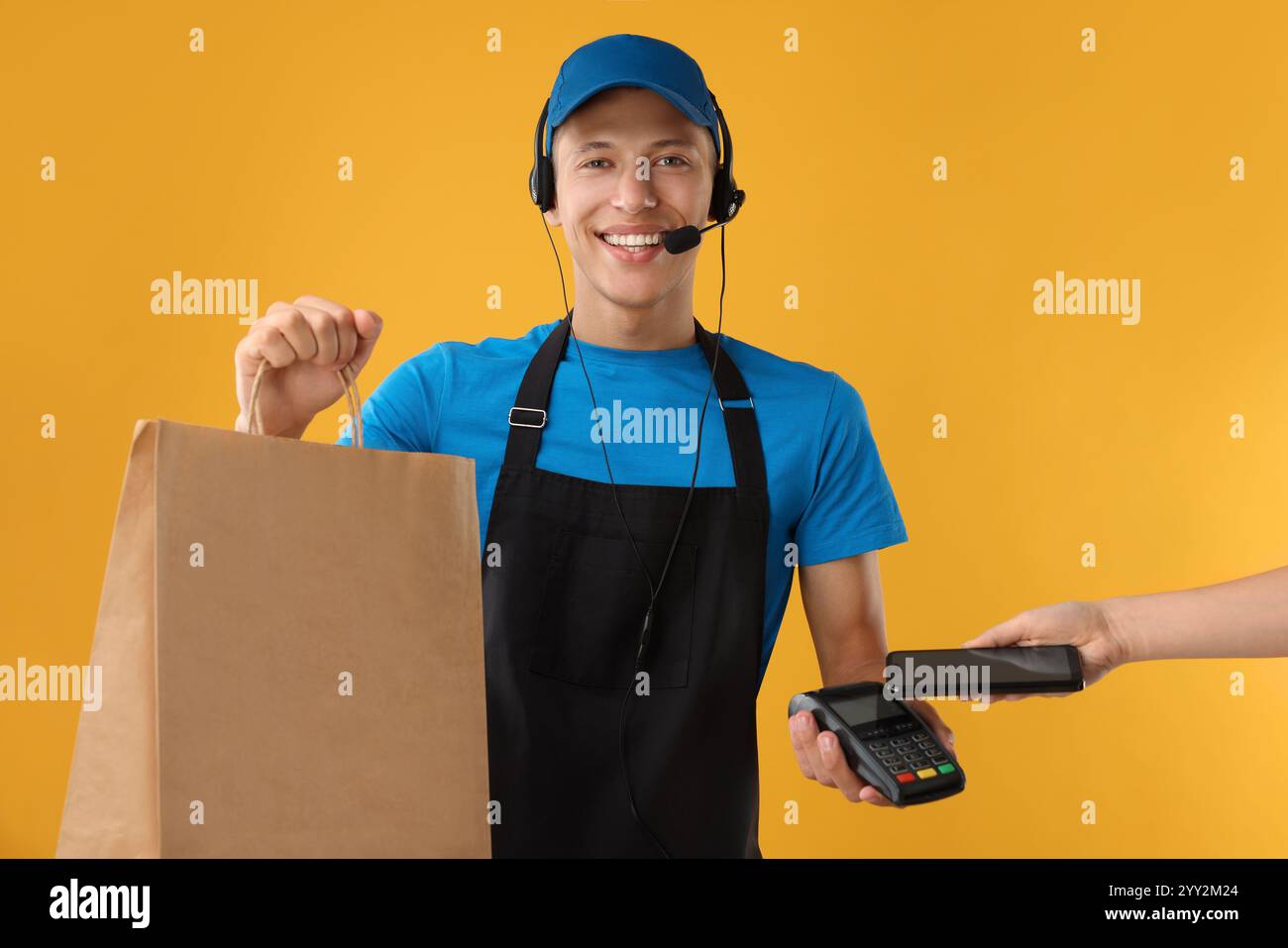 Fast-food worker taking payment from client via terminal on orange ...