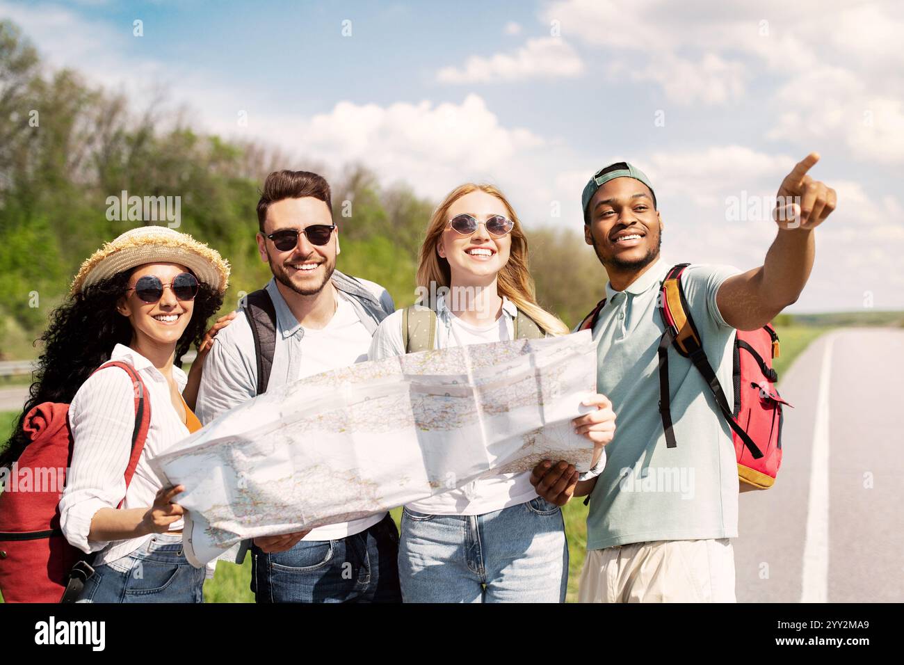 Group of multiethnic friends checking map, choosing route during road ...