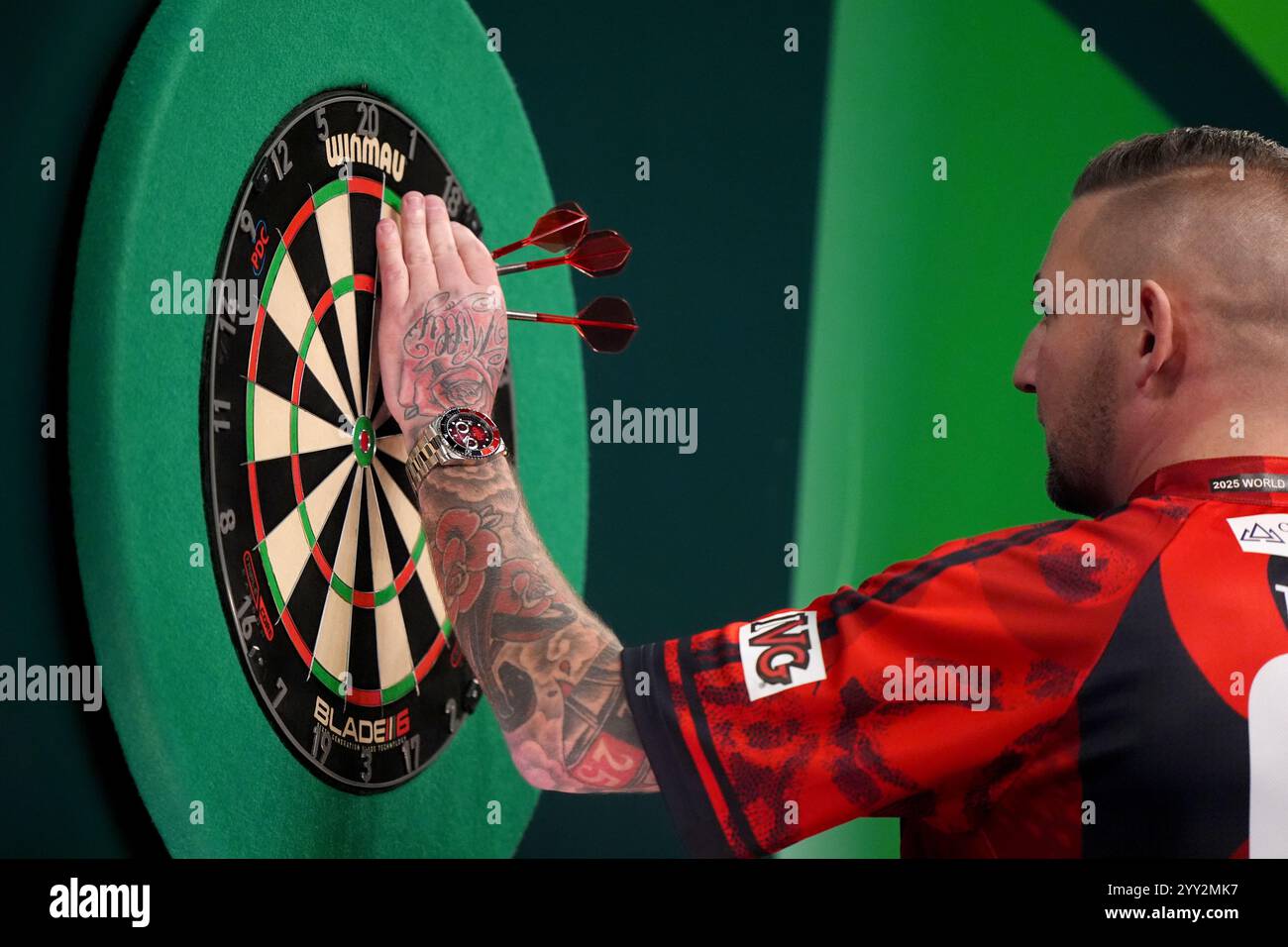 Nathan Aspinall retrieves his darts during his second round match ...