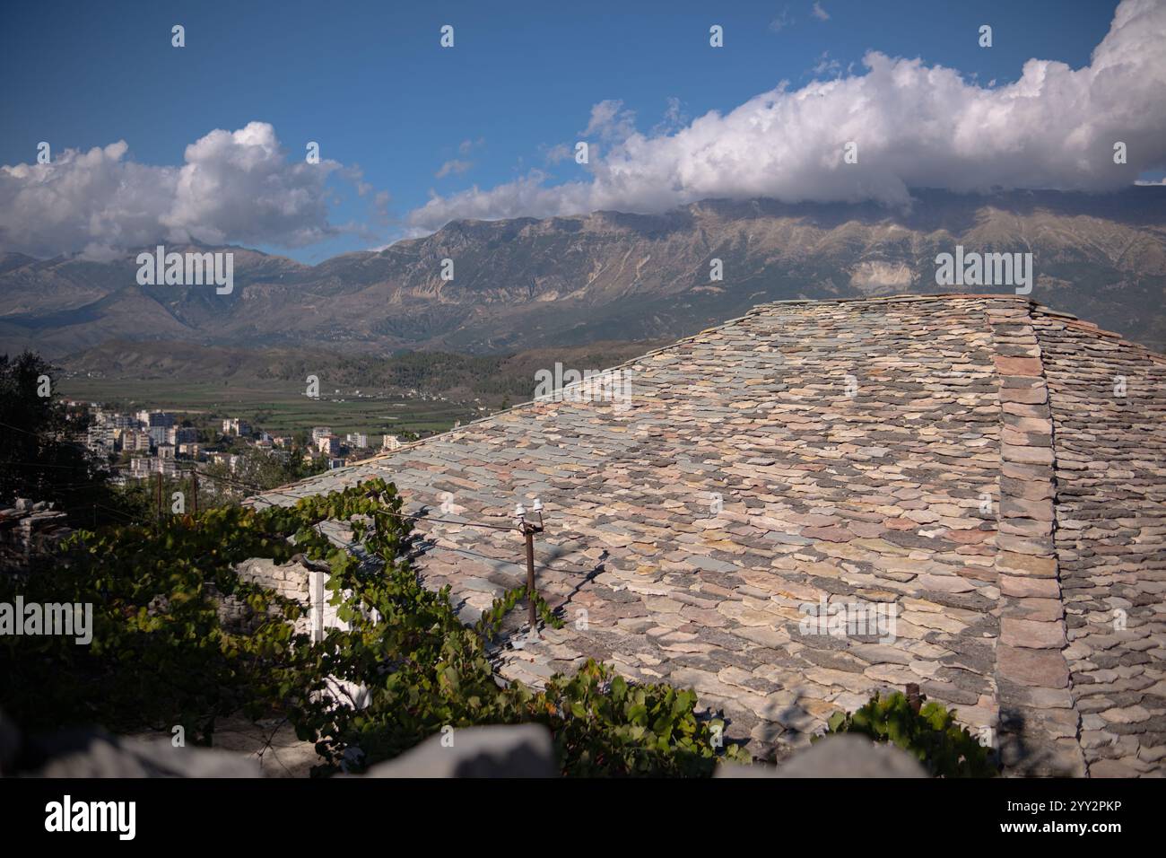 View of stone roofs, mountains and clouds. Traditional Albanian roof ...