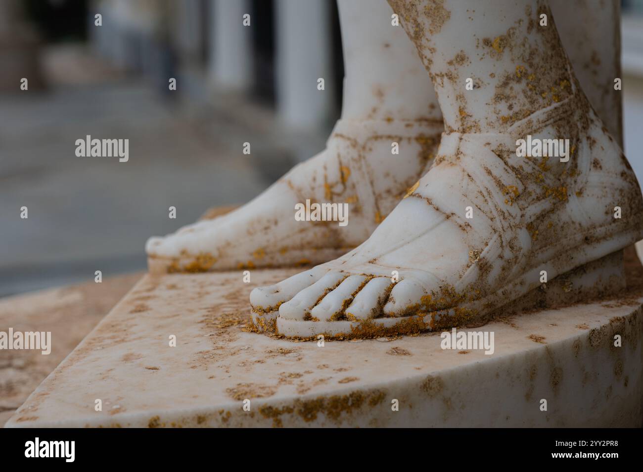 An antique statue made of white stone with a layer of old dirt stands ...