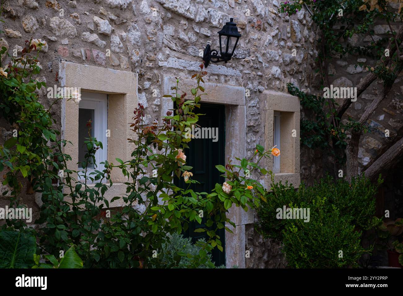 The facade of an old stone house with a door and windows in massive ...