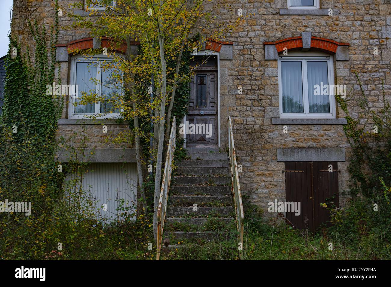 The facade of an old stone house with a door and windows in massive ...