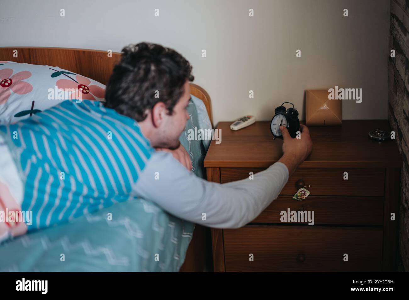 Man waking up in morning reaching for alarm clock Stock Photo - Alamy