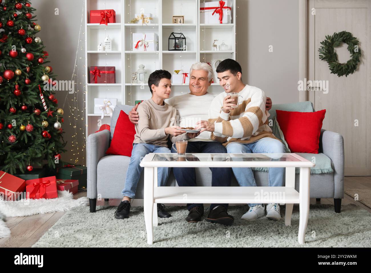 Little boy with dad and grandfather eating cookies at home on Christmas ...