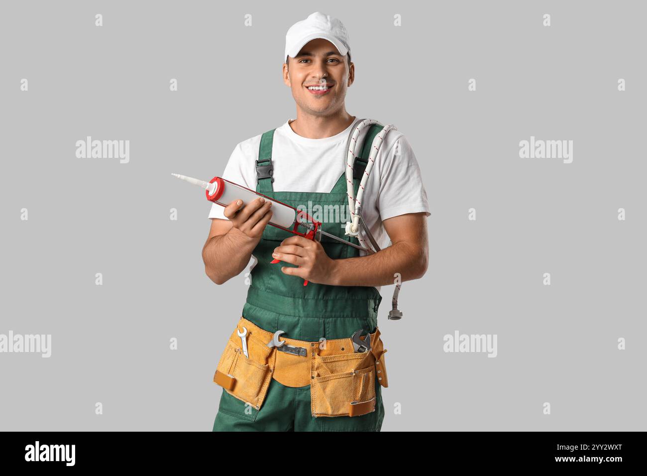 Male plumber with caulking gun on light background Stock Photo - Alamy