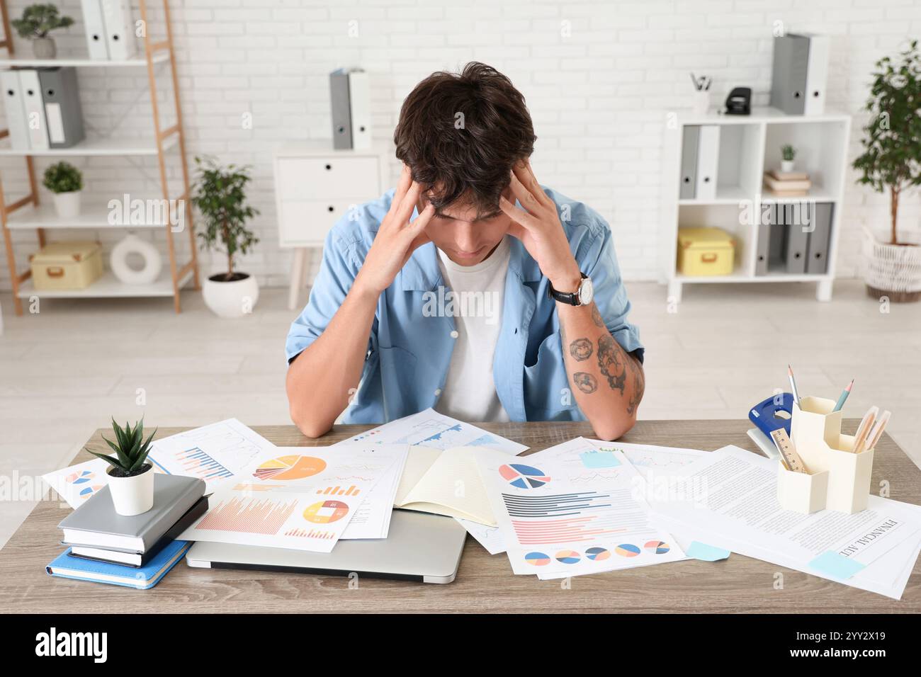 Stressed young man sitting at desk in office Stock Photo - Alamy