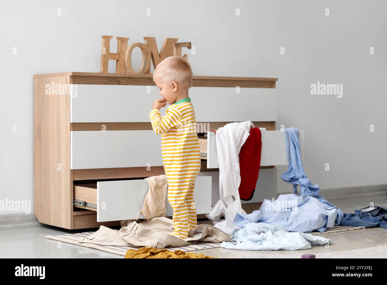 Naughty baby boy with scattered clothes in messy room Stock Photo - Alamy