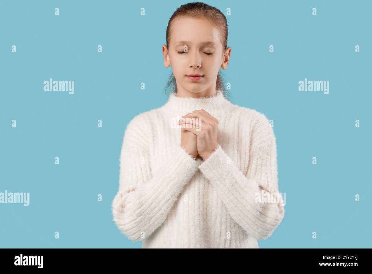 Teenage girl praying on blue background Stock Photo - Alamy