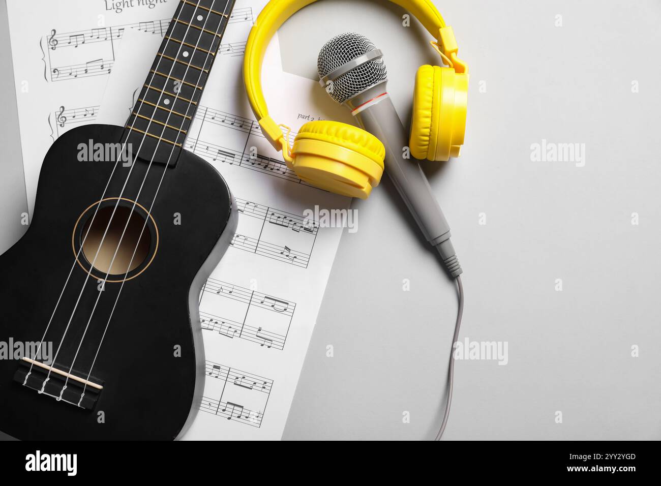 Ukulele, modern headphones, microphone and music sheets on grey ...