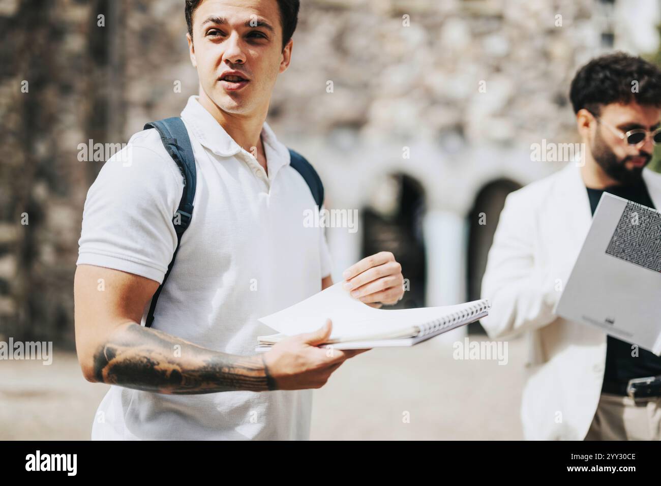 Two students studying together outdoors after class in urban setting ...