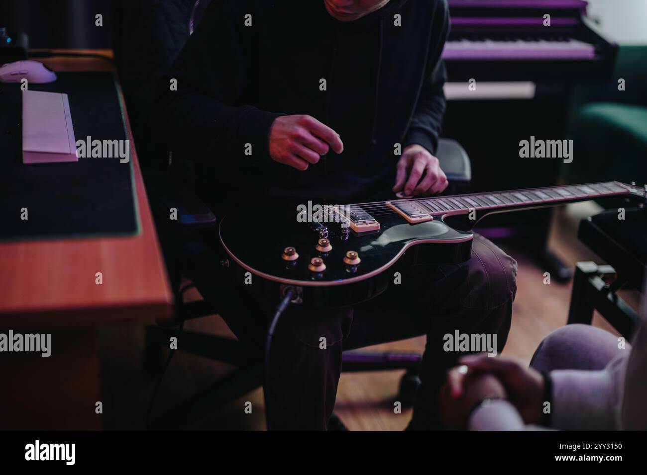 Person tuning an electric guitar in a cozy music studio setting Stock ...