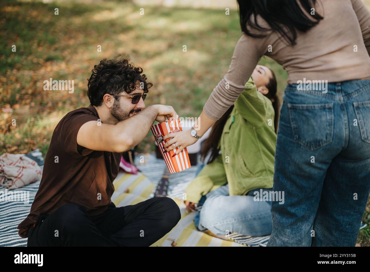 Friends enjoying a picnic with popcorn and laughter outdoors Stock ...