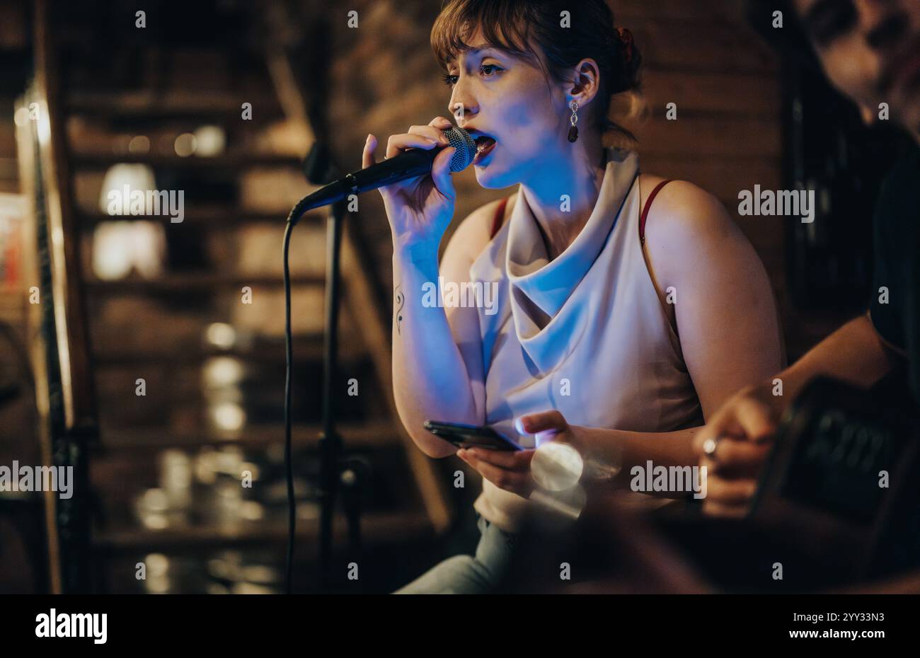 Young woman passionately singing into a microphone at a cozy intimate ...