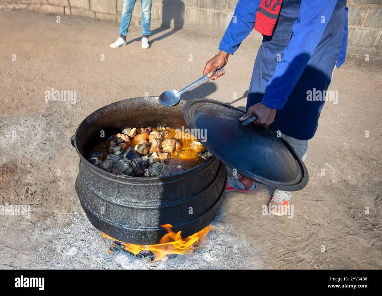 cooking traditional boiled cow heels outdoors, african street vendor ...