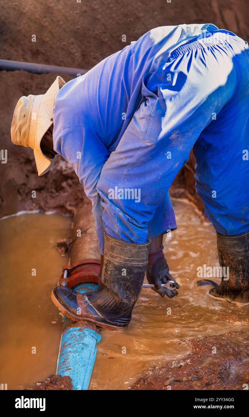 african american plumber construction worker fixing a blocked drainage ...