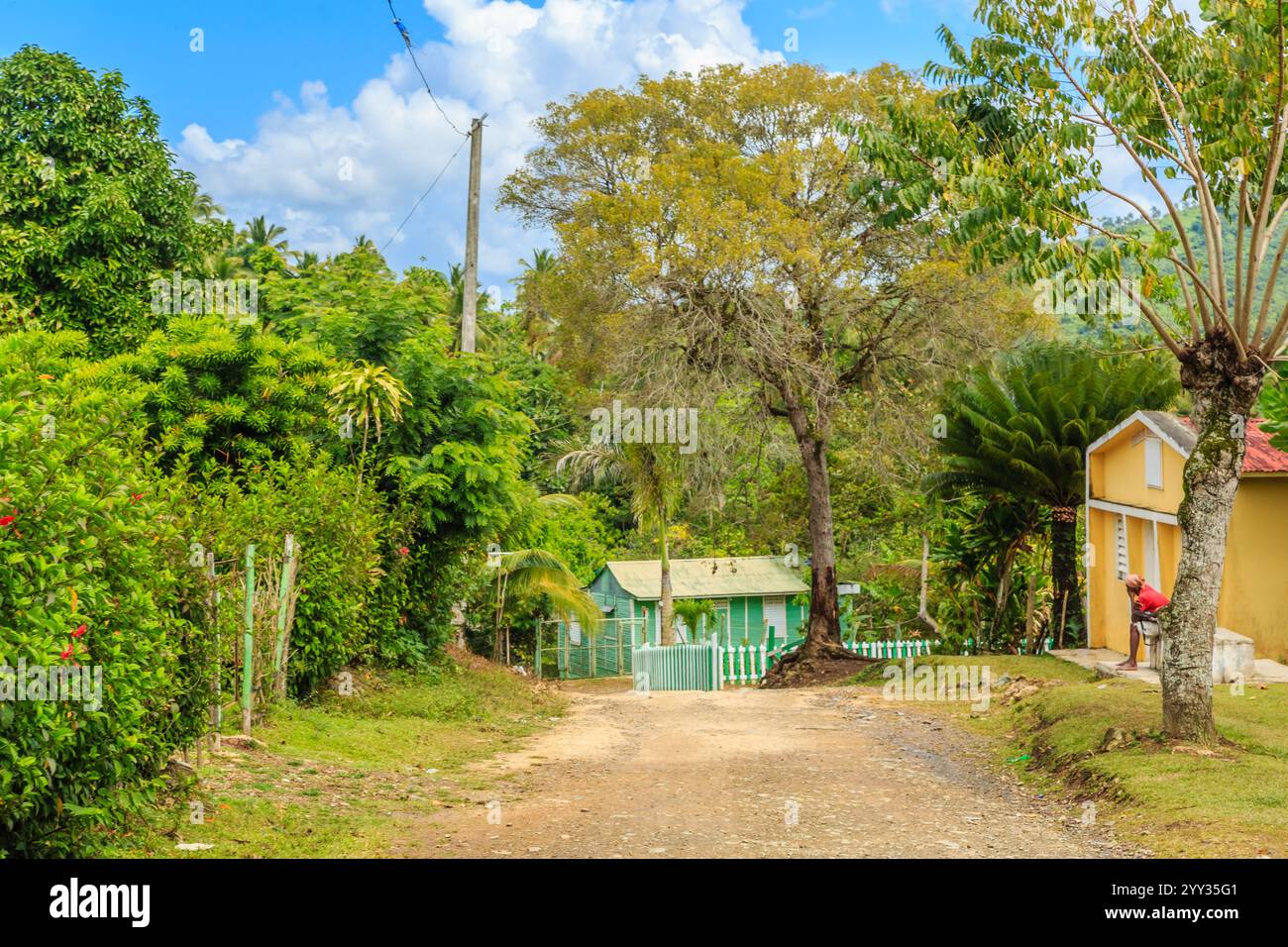 A small town with a dirt road and a house with a green roof. The road ...