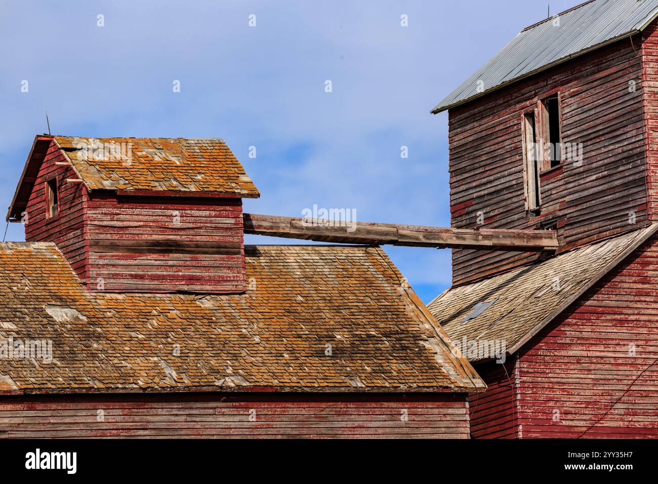 A red barn with a slanted roof and a wooden beam. The roof is covered ...