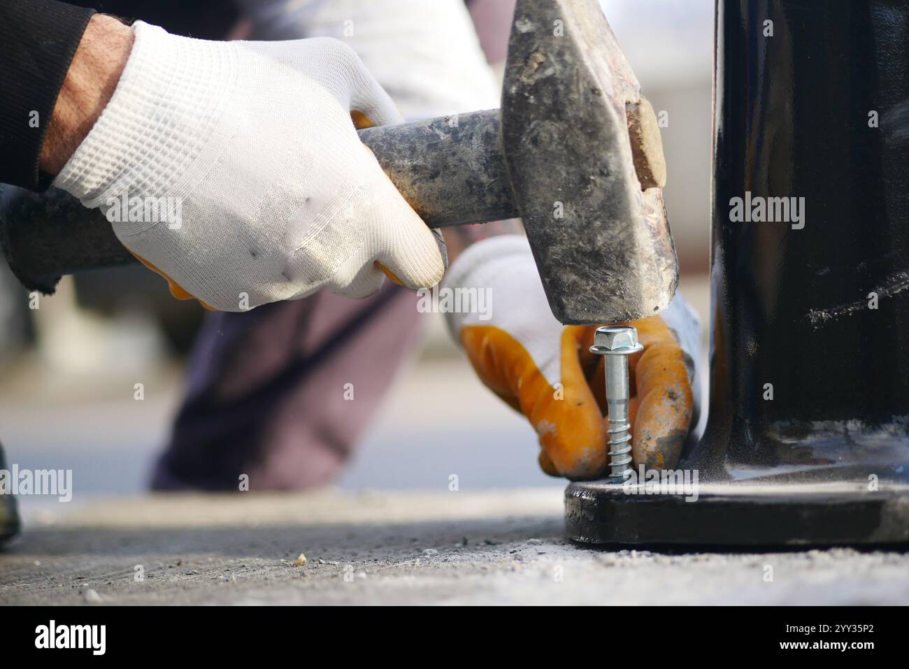 A worker hammers a bolt into a large construction structure for ...