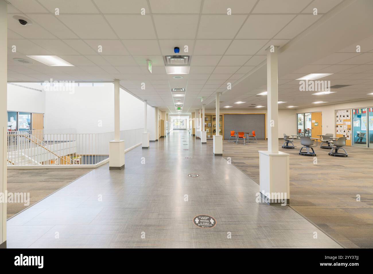 Middle school hall and common space with classrooms and stairs in light ...