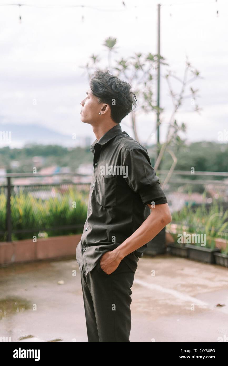 A Southeast Asian man putting his hand in his pants pocket, casually ...