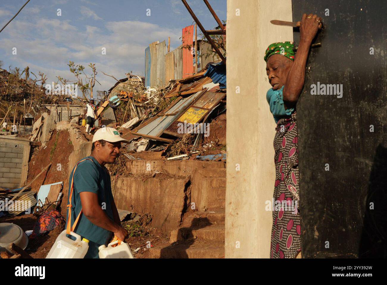 People walk past debris in the Kaweni slum Thursday, Dec. 19, 2024, on ...