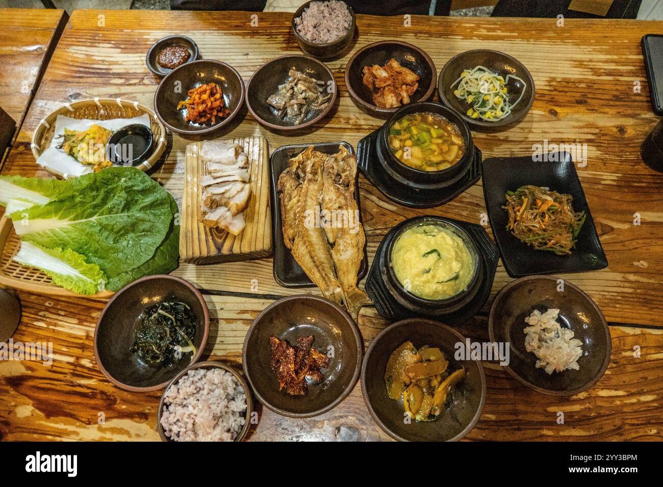 Traditional Jeju Island feast, fish, black pork, and banchan side ...