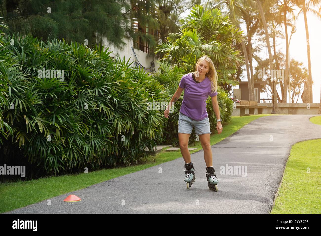 A woman is rollerblading gracefully on a road located in a park Stock ...