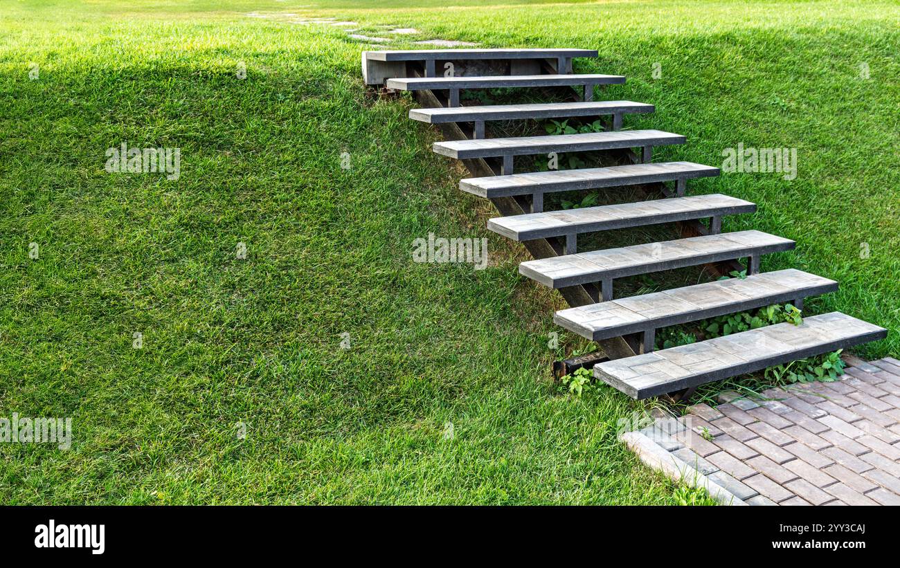 Modern outdoor staircase on a green grassy slope, leading to a paved ...