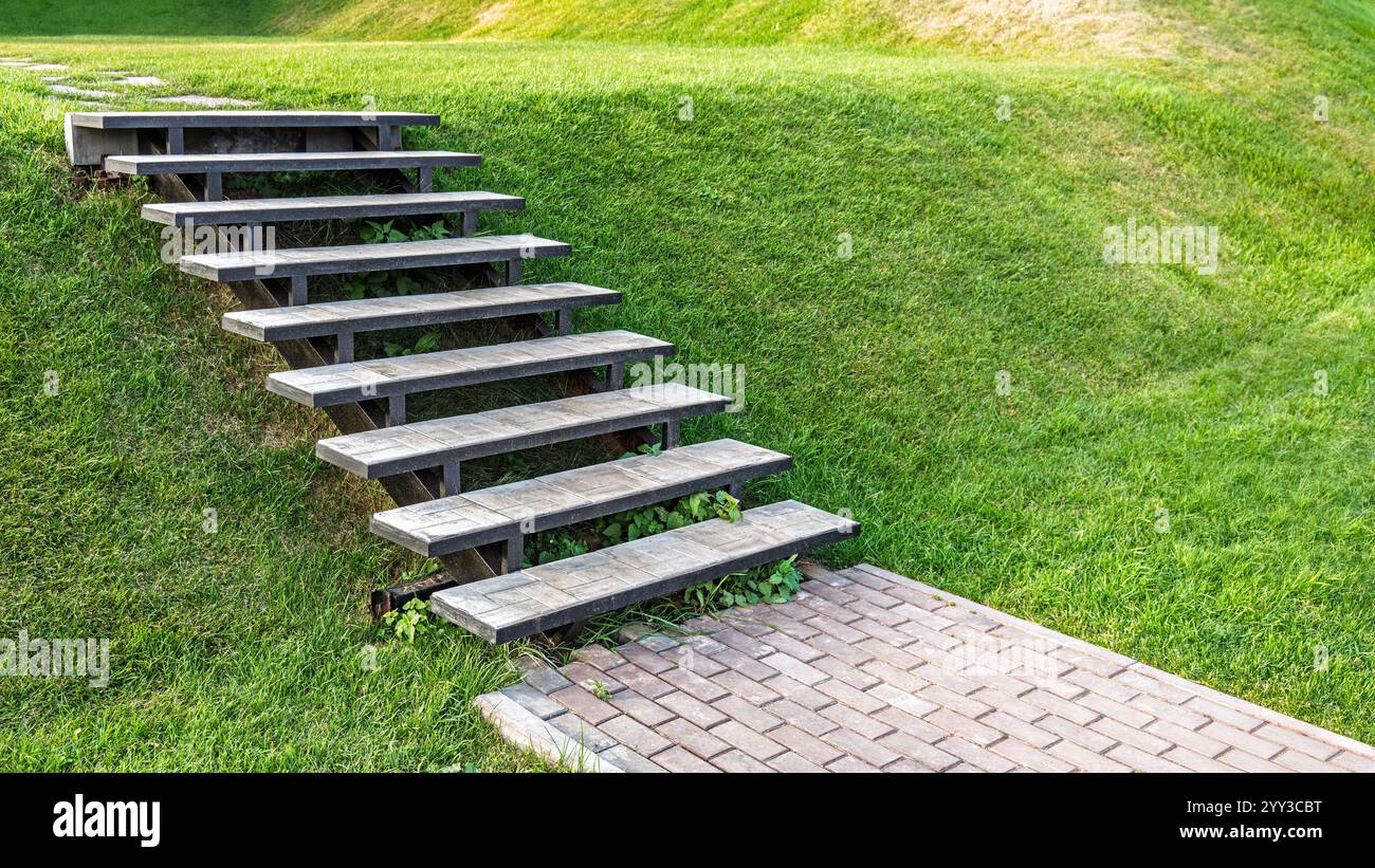 Modern outdoor staircase on a green grassy slope, leading to a paved ...
