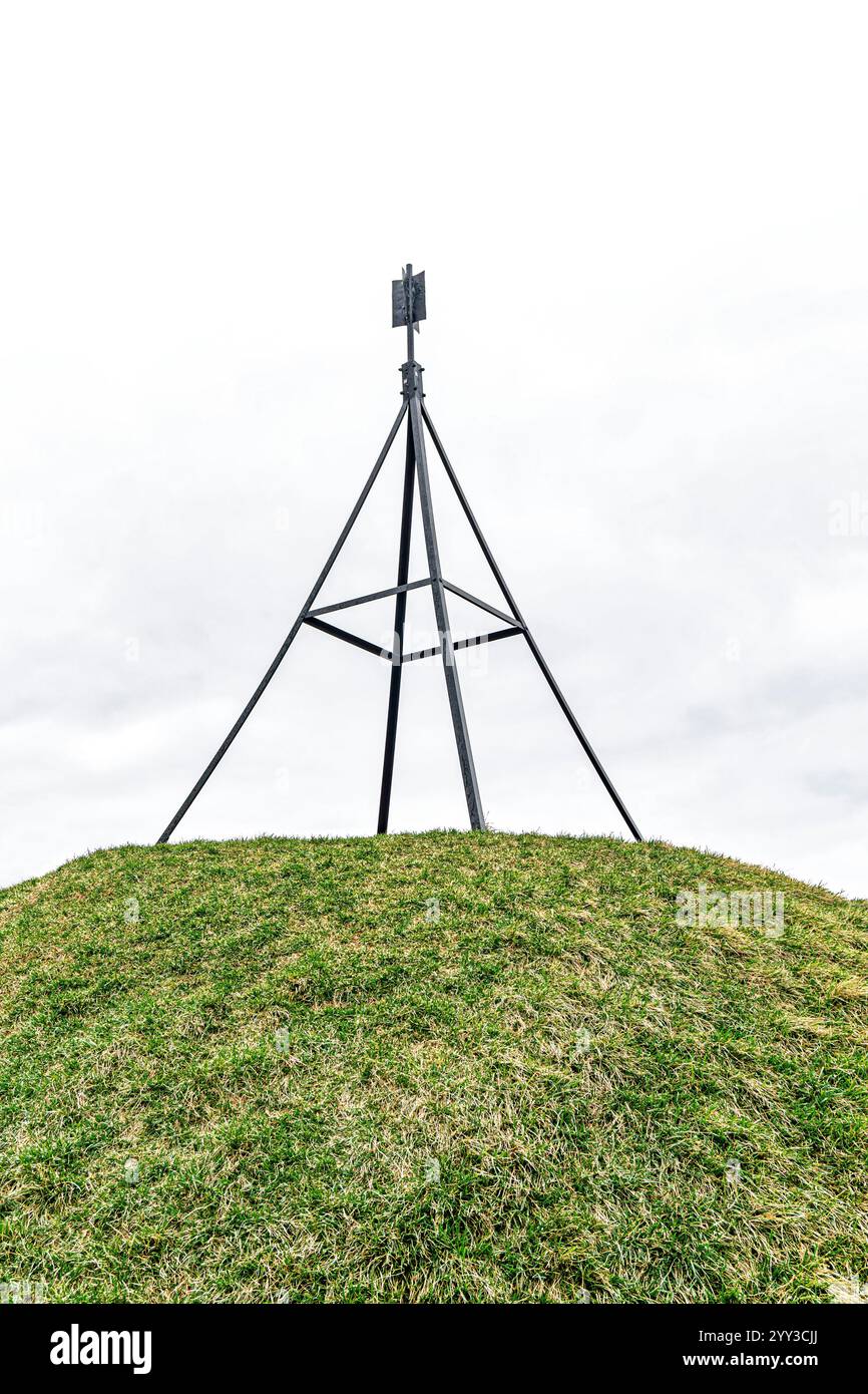 Metal structure on lush green hilltop with cloudy white sky in ...