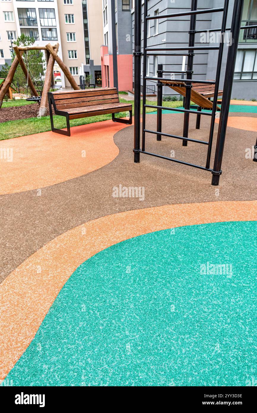 Playground area with vibrant rubber flooring, benches, and climbing ...