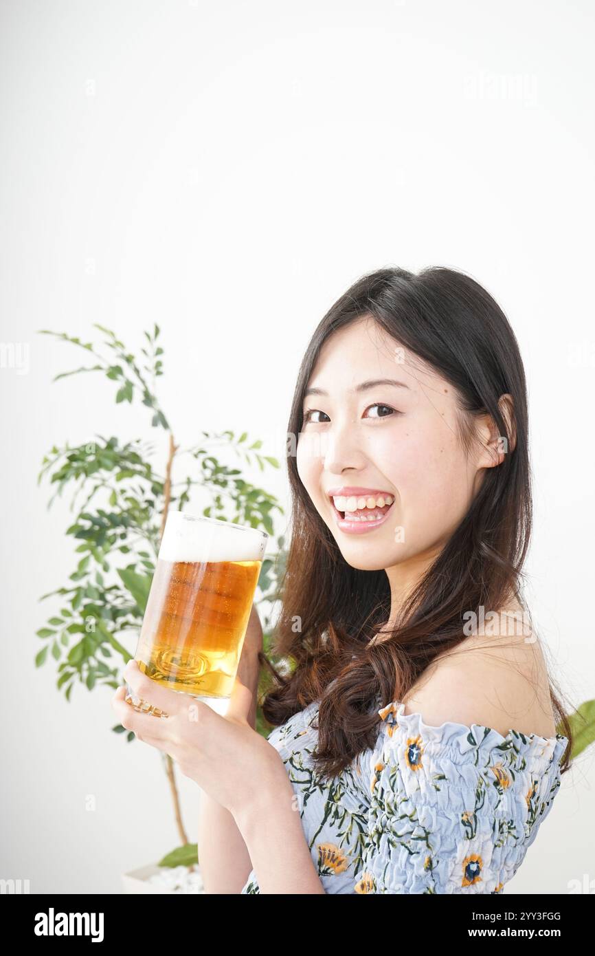 Young woman drinking beer in room Stock Photo - Alamy