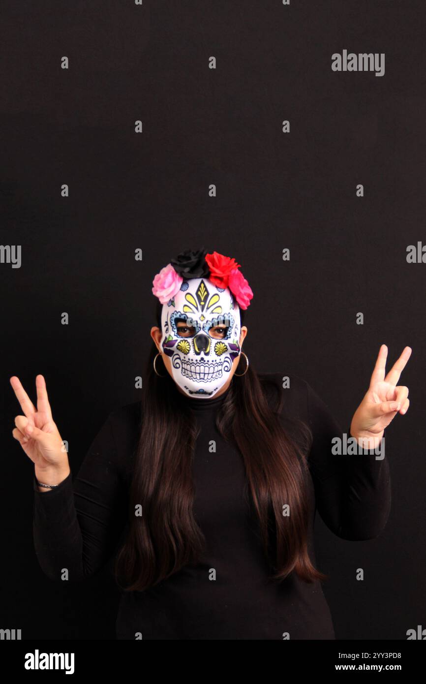 Mexican adult woman with catrina mask shows the sign of love and peace ...