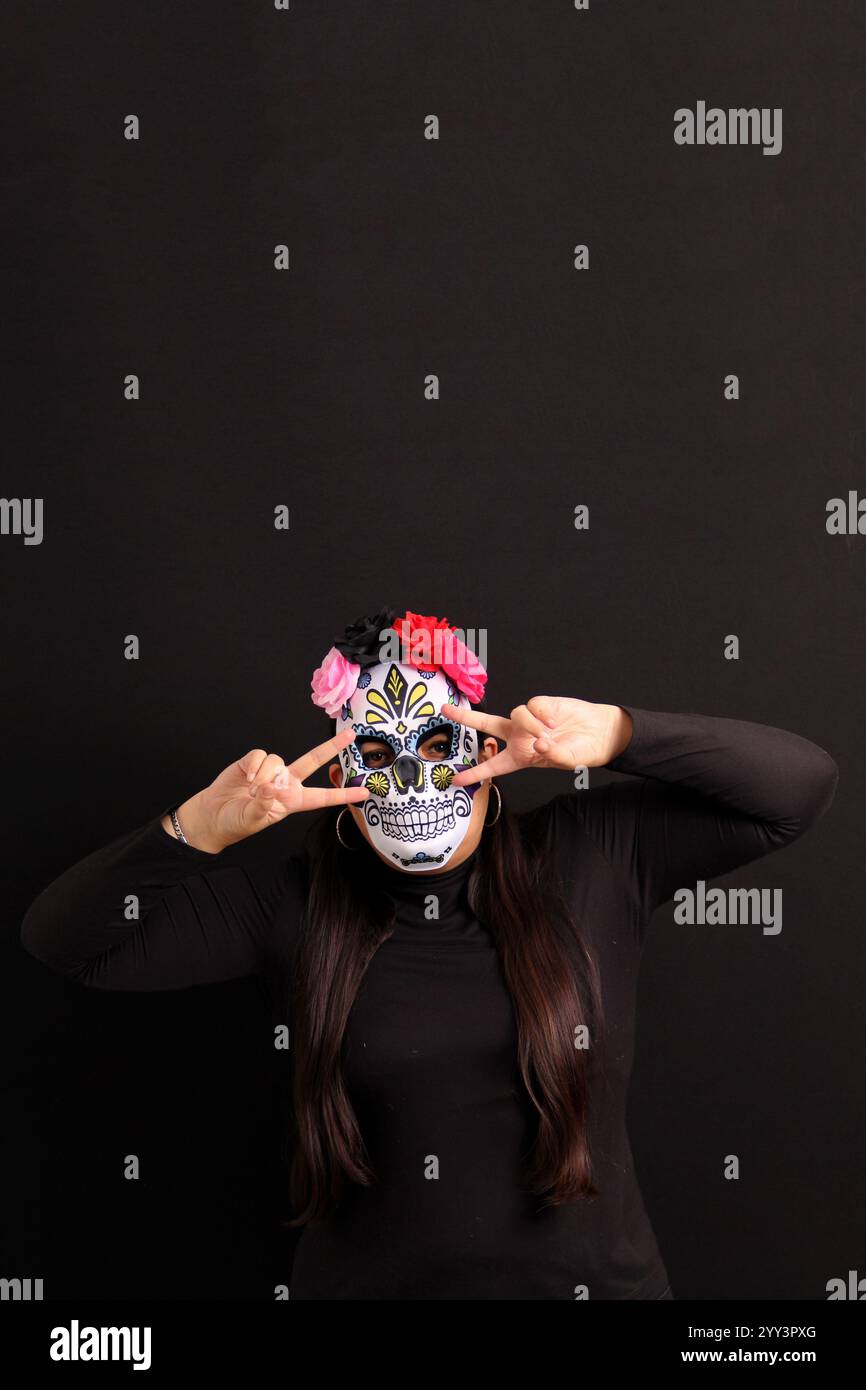 Mexican adult woman with catrina mask shows the sign of love and peace ...