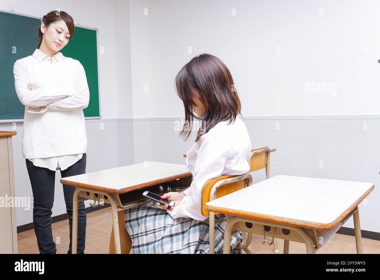 Student using a smartphone during class and teacher cautioning her ...