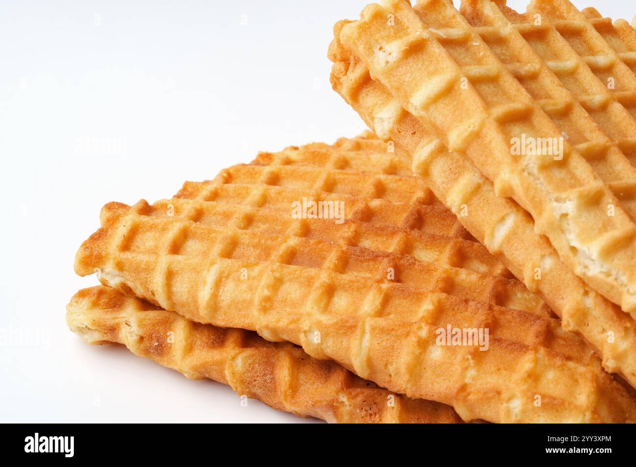Crispy freshly made waffles stacked on a clean white surface ready to ...