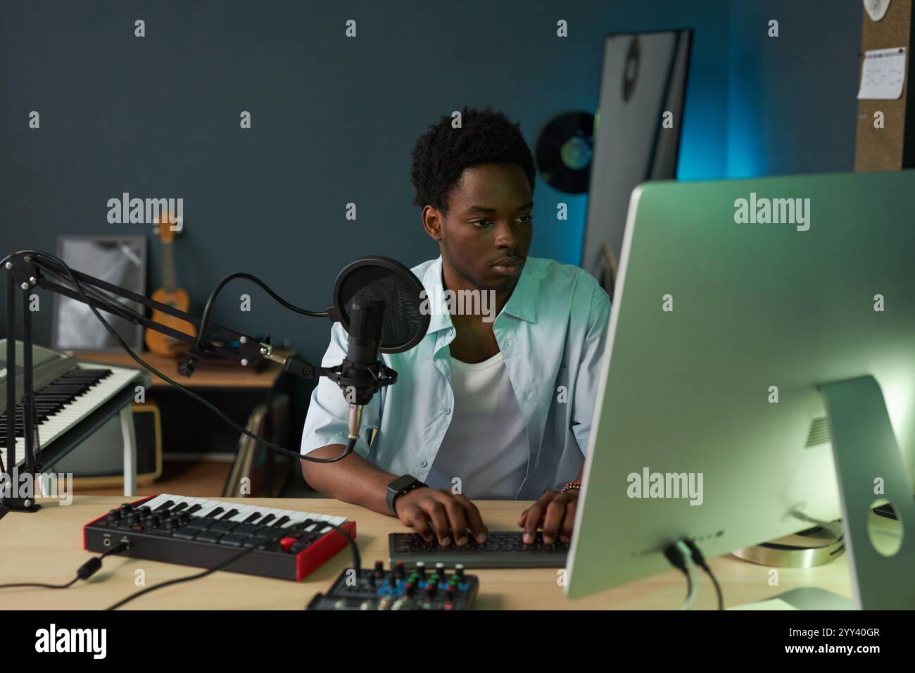 Producer sitting at his workplace and using computer to make song in ...