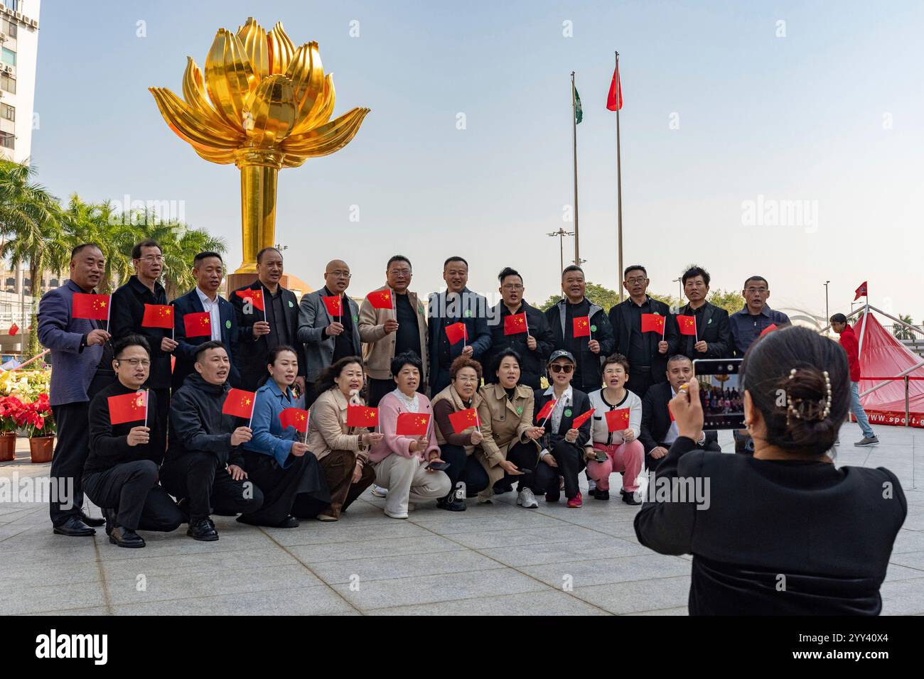 Visitors hold Chinese national flags as they pose for photos at the ...