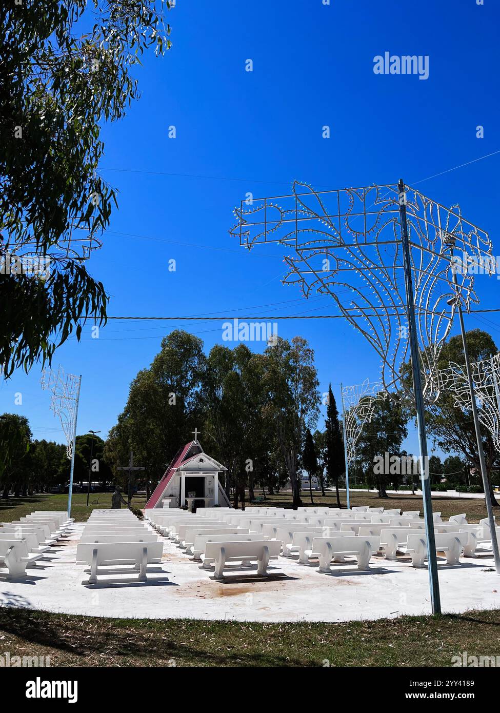 An outdoor church setup with white benches and decorative lights ...