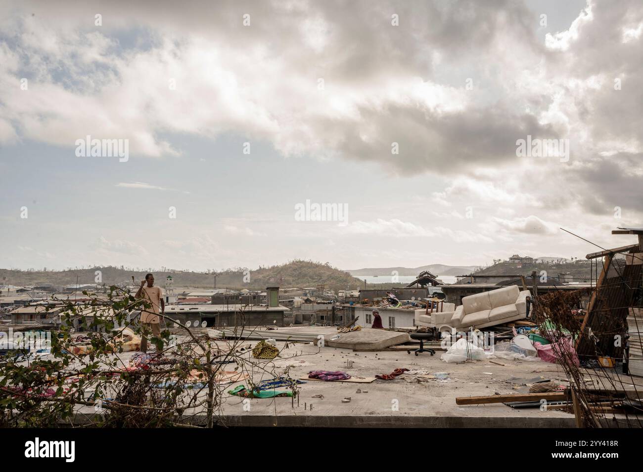 A man stands on his roof in the Kaweni slum on the outskirts of ...
