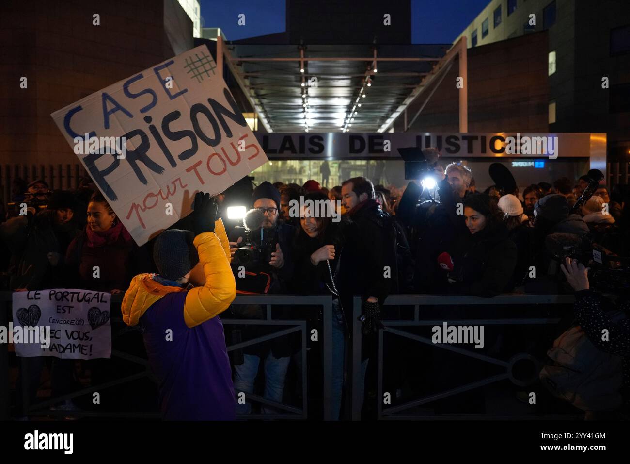 A man with a placard reading "Jail for everyone" walks past the media ...