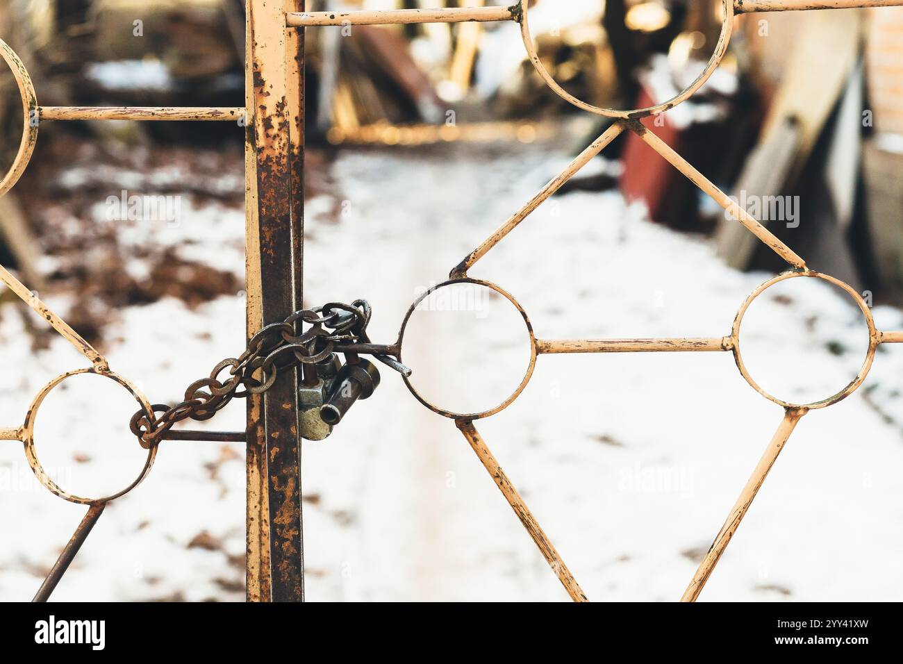 Rusty old metal gate with lock. In gloomy winter weather, a metal lock ...