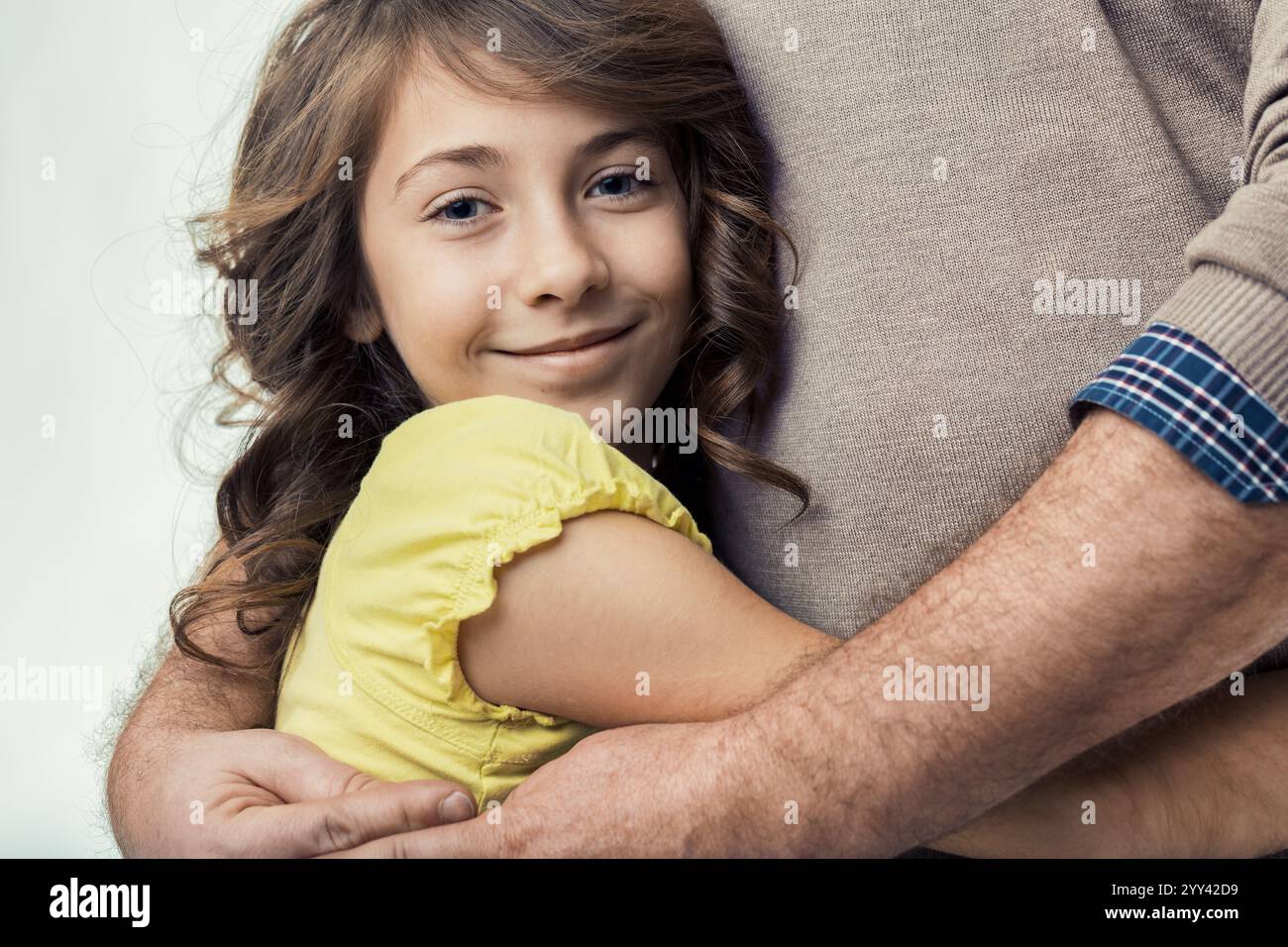 Young daughter embracing her father, arms wrapped around him in a ...